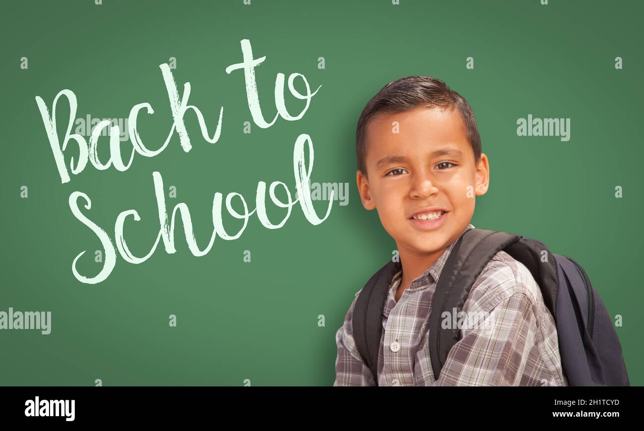 Cute Hispanic Boy Wearing A Backpack In Front of Chalk Board with Back ...