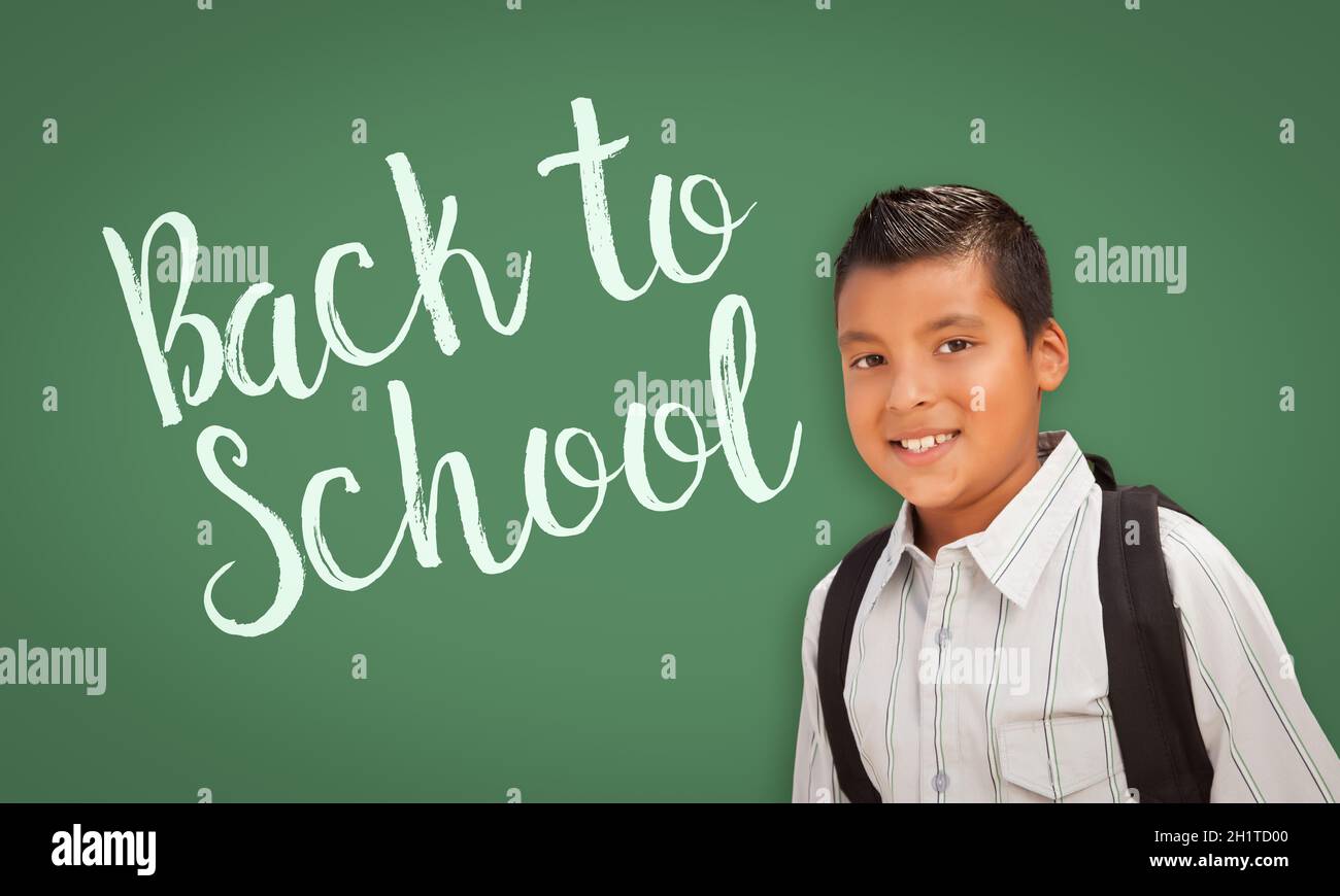 Cute Hispanic Boy Wearing A Backpack In Front of Chalk Board with Back ...