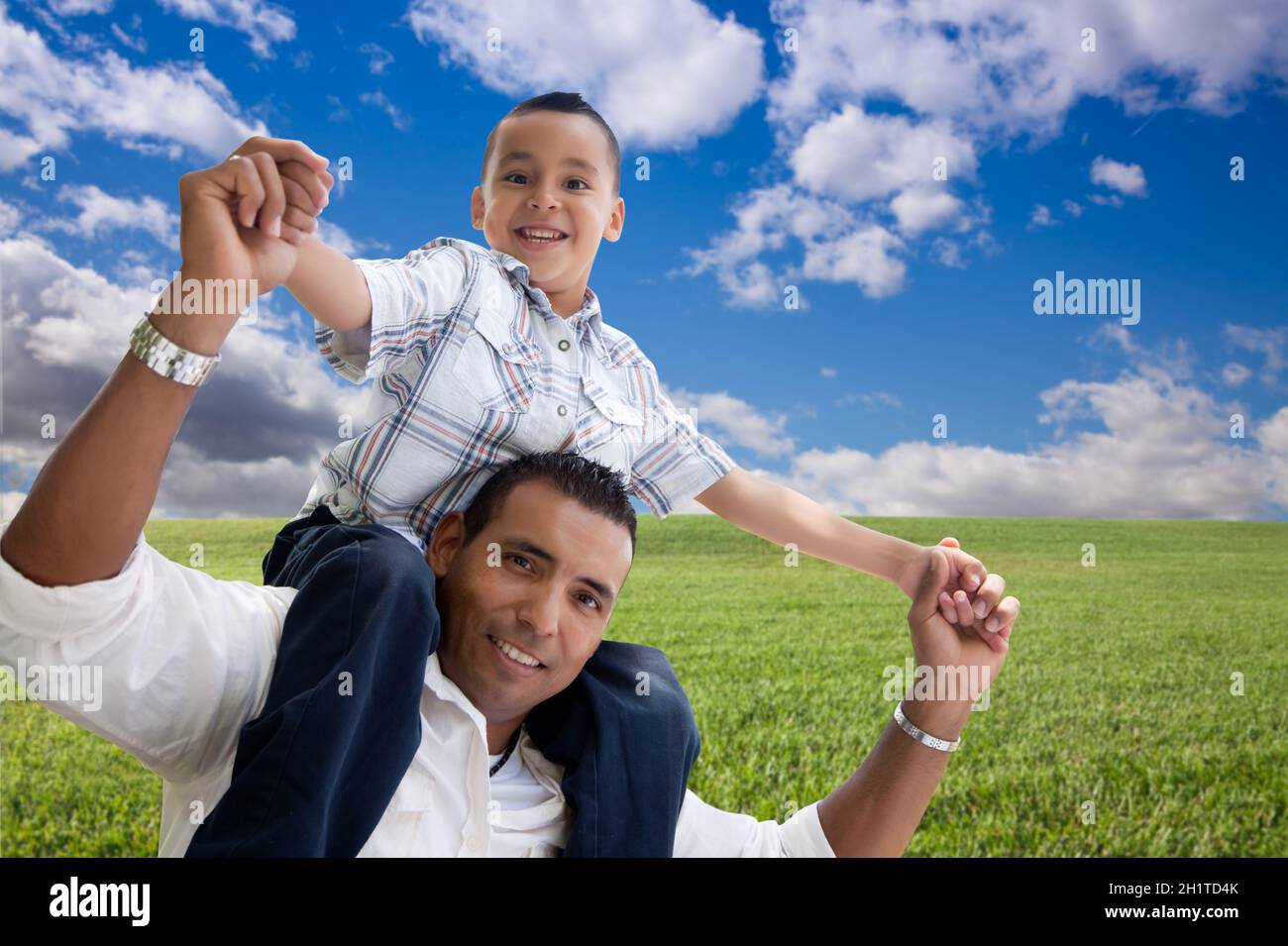 Happy Hispanic Father and Son Over Grass Field, Clouds and Blue Sky ...