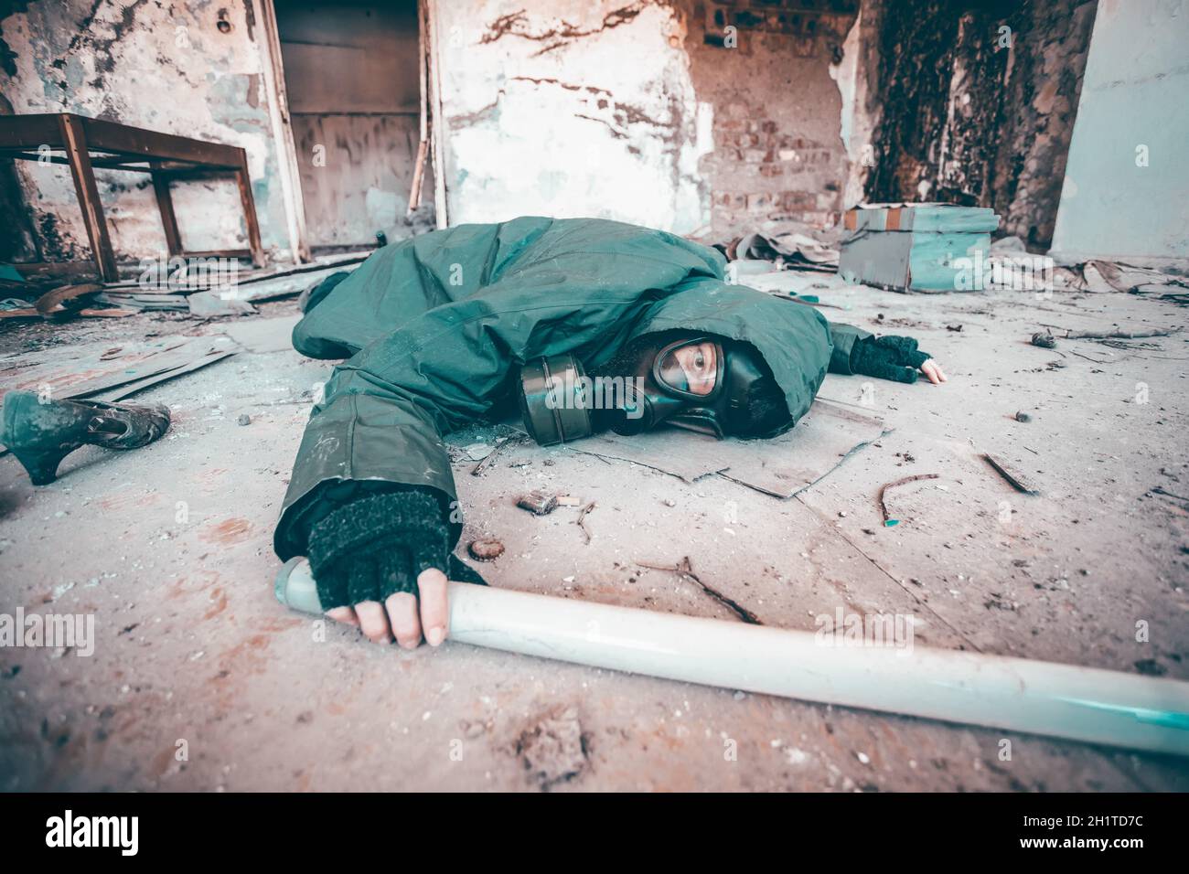 Post apocalyptic survivor in gas mask fallen on the ground in a ruined ...
