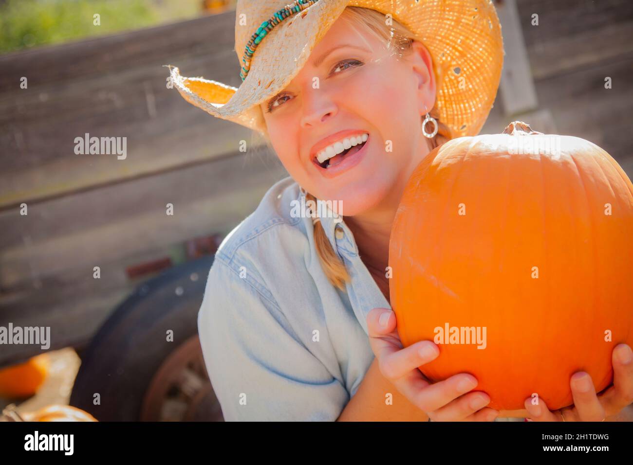 Beautiful Blond Female Rancher Wearing Cowboy Hat Holds a Pumpkin in a ...