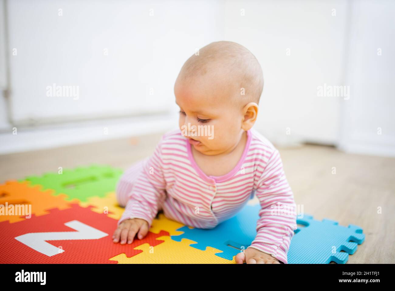 Adorable baby lying face down on colorful children mat with letters ...