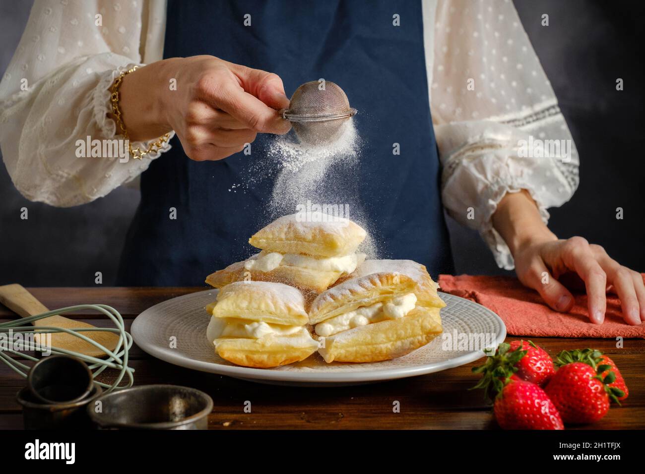 powdered icing sugar sprinkling from a sieve in woman's hand, cooking ...