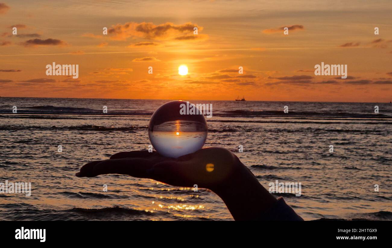 Hand holding glass ball against a be Stock Photo - Alamy