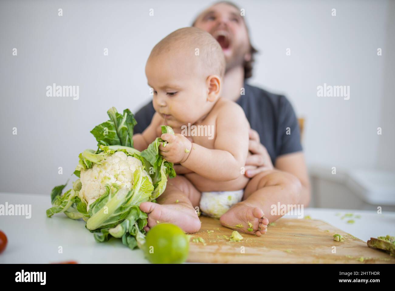 Father laughing hysterically and holding his happy baby daughter above ...