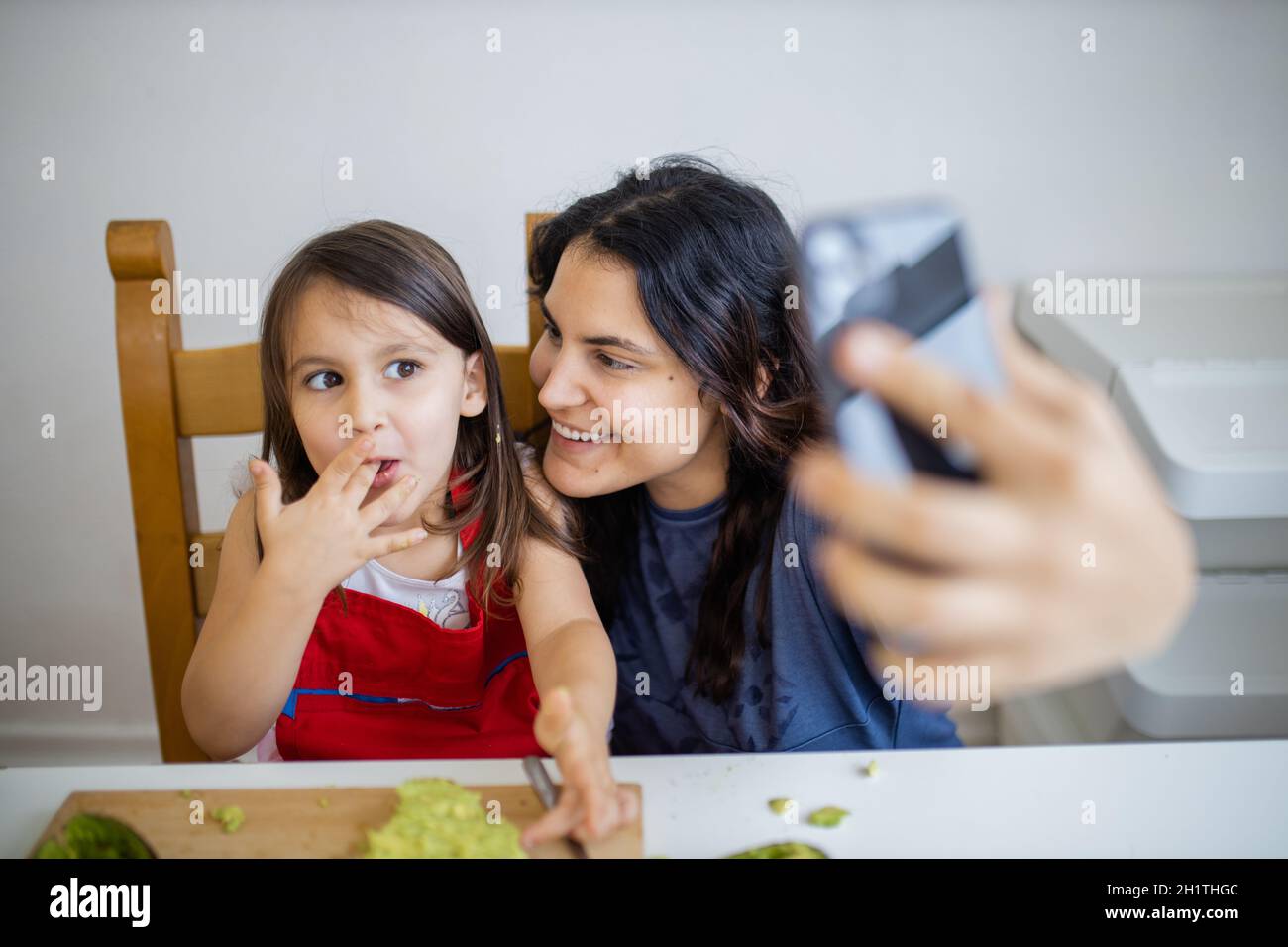 Happy mother and daughter taking selfie while eating toast with avocado ...