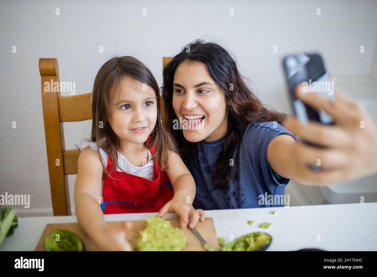 Happy excited mother and daughter taking selfie while eating toast with ...