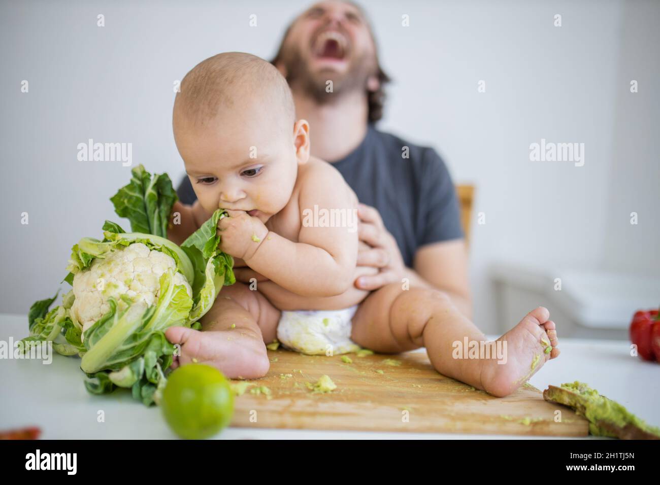 Father laughing hysterically and holding his happy baby daughter above ...