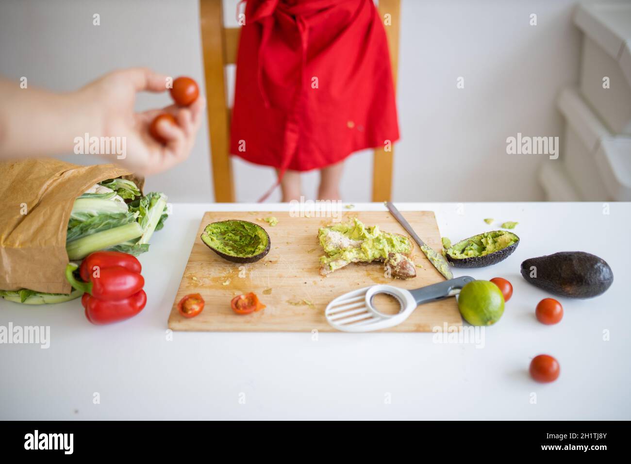 Female hand giving cherry tomatoes to little girl at a table making ...