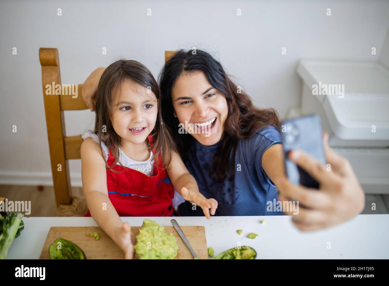 Happy excited mother and daughter taking selfie while eating toast with ...