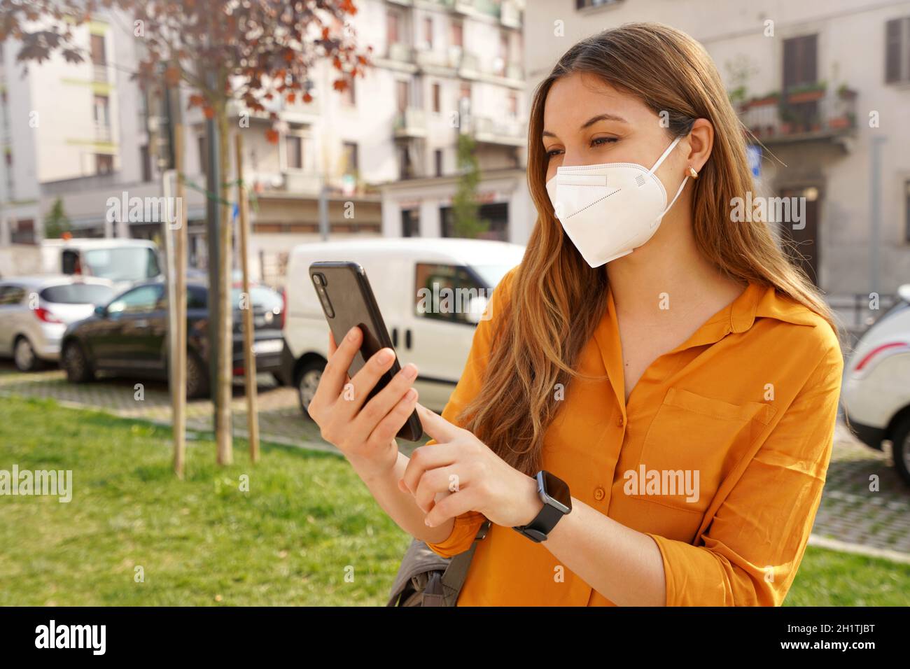 Pretty girl with smartwatch wearing KN95 FFP2 face mask using mobile ...