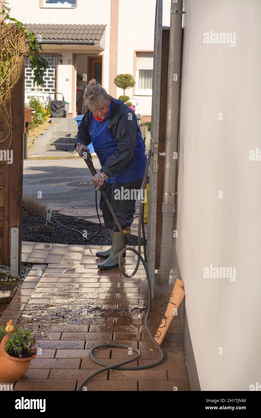 Worker cleaning driveway with gasoline high pressure washer splashing ...