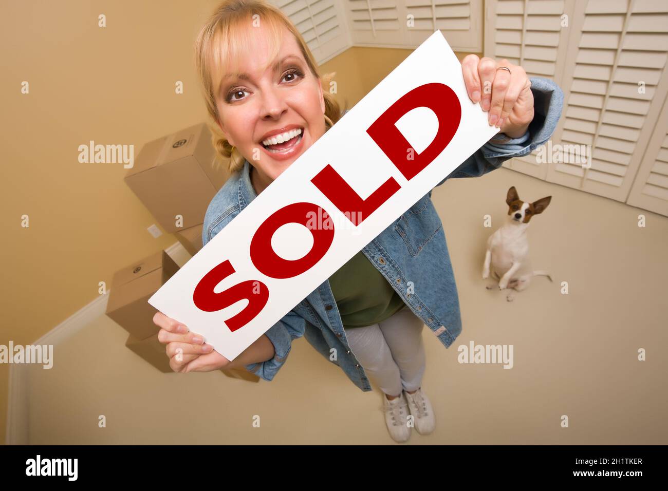 Excited Woman and Doggy with Sold Real Estate Sign Near Moving Boxes in ...