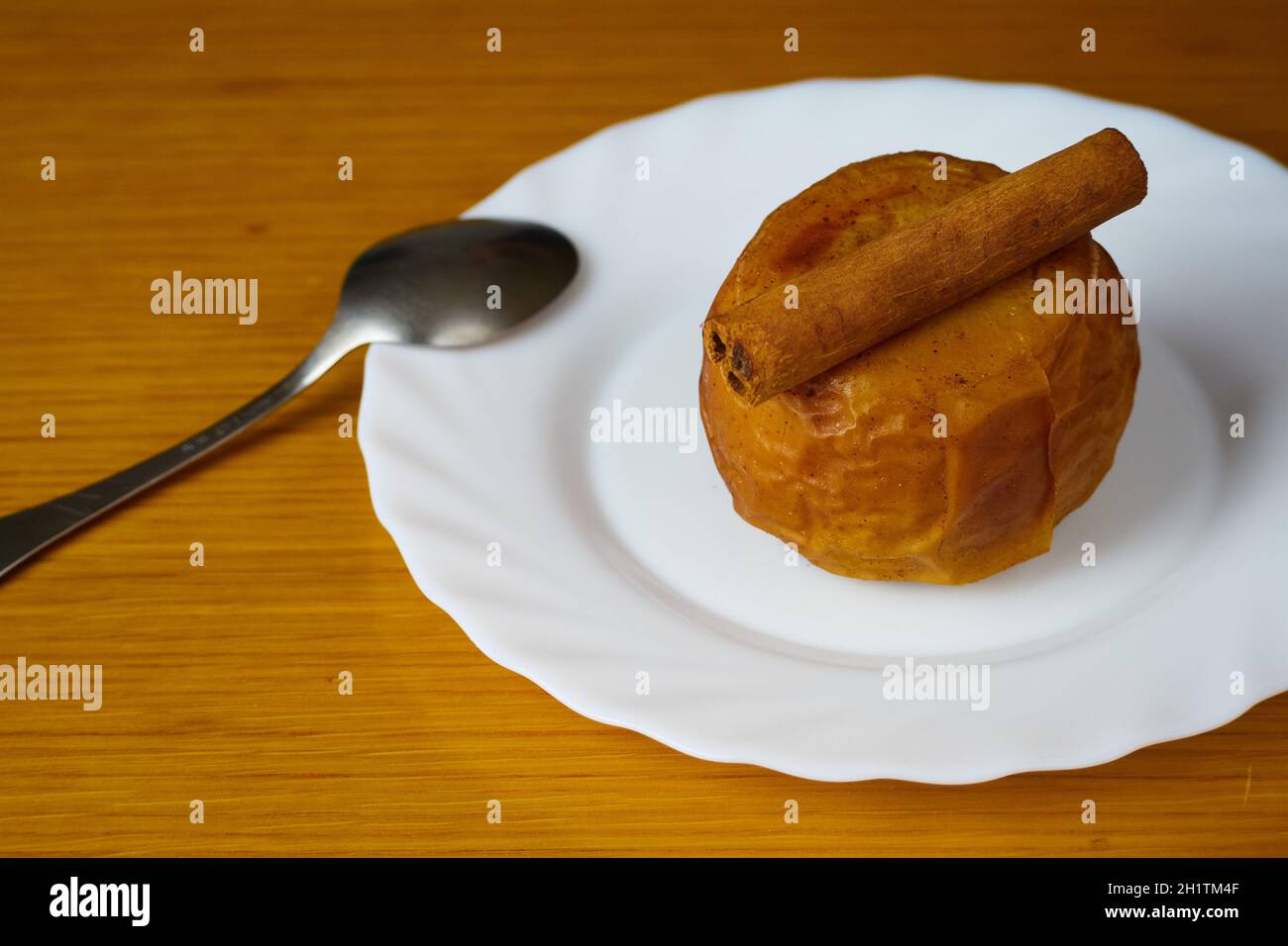 Baked Apple decorated with a cinnamon stick and a metal spoon on a ...