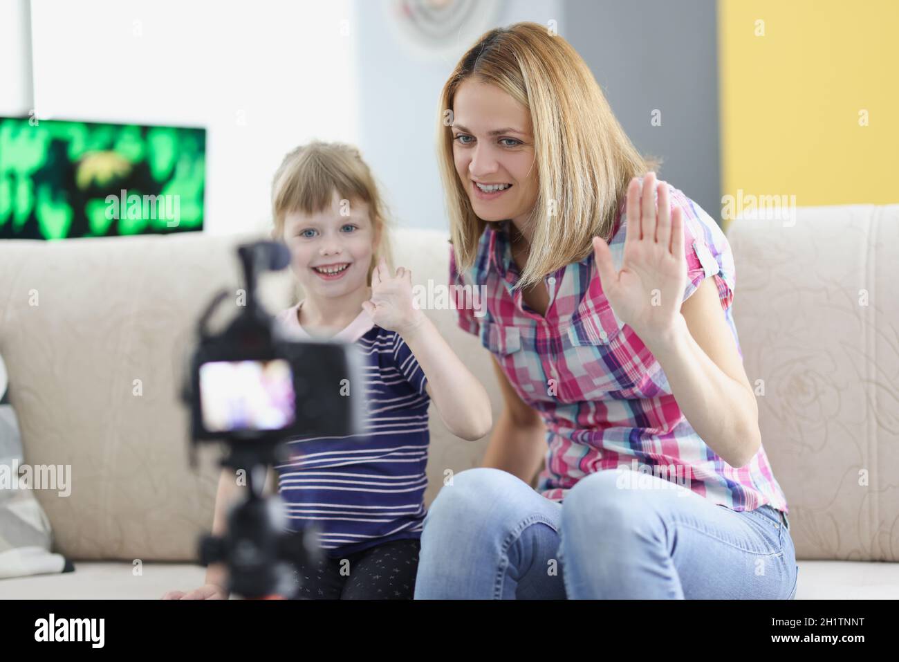 Mom and daughter record video greeting on camera Stock Photo - Alamy