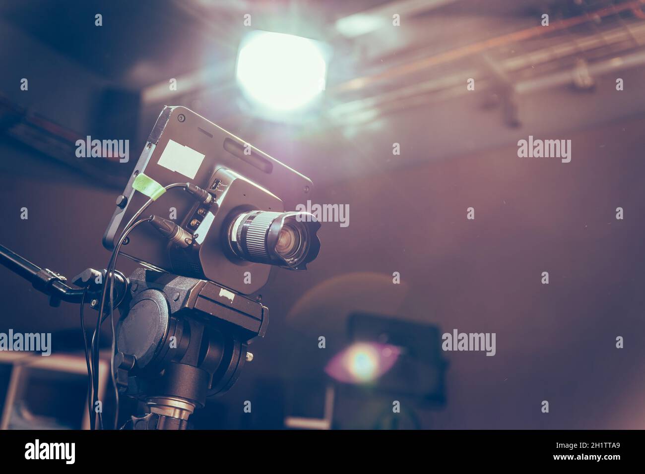 Film camera on a tripod in a television broadcasting studio, spotlights ...