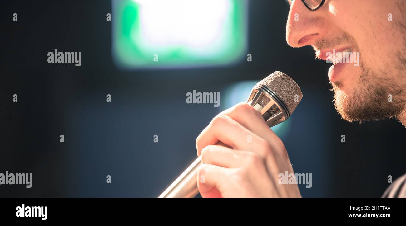 Young man on the stage is talking into a microphone, speech Stock Photo ...