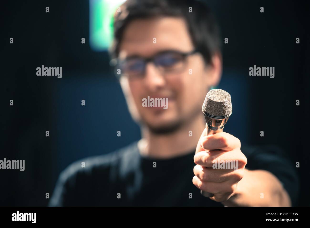 Young man on the stage is talking into a microphone, speech, face is ...