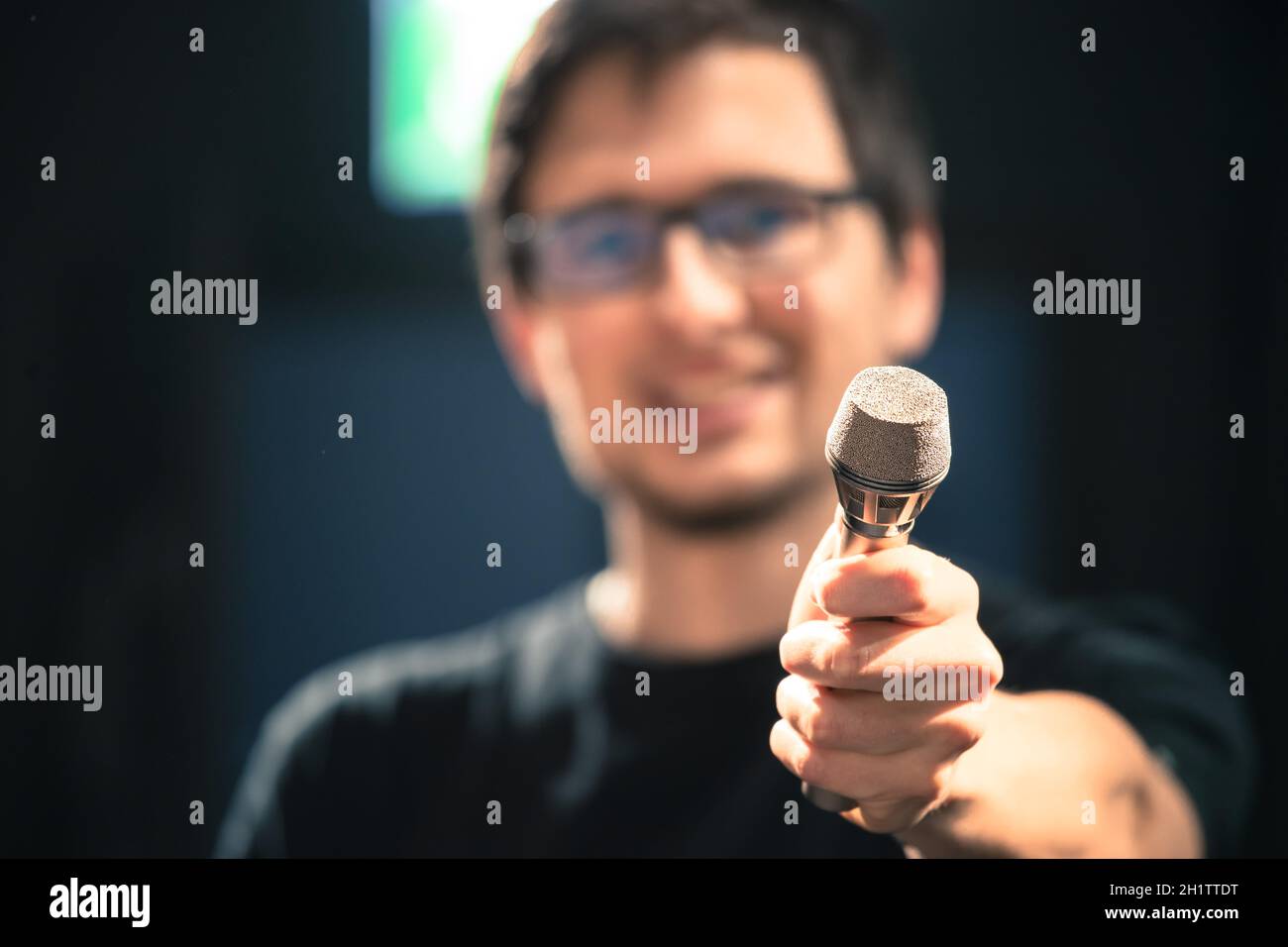 Young man on the stage is talking into a microphone, speech, face is ...