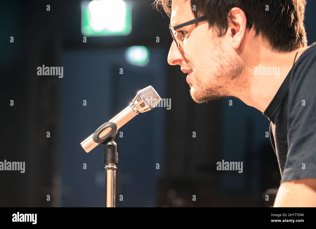 Young man on the stage is talking into a microphone, speech Stock Photo ...