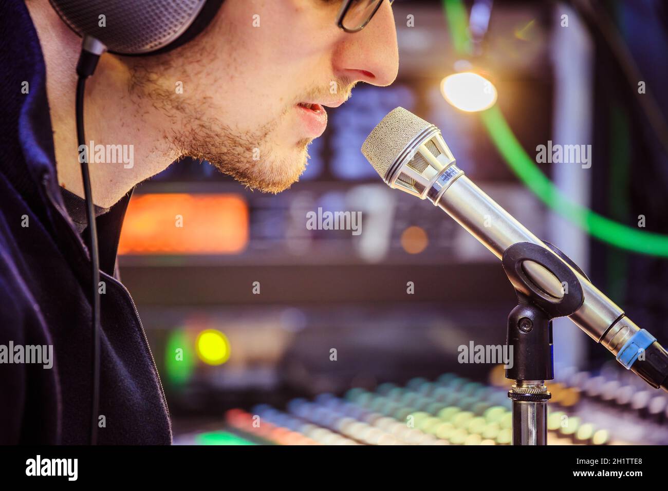 Young man is sitting in the recording studio and talks into the ...