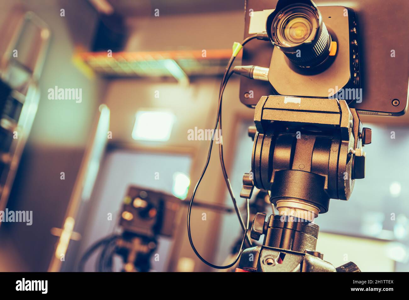 Film camera on a tripod in a television broadcasting studio, spotlights ...