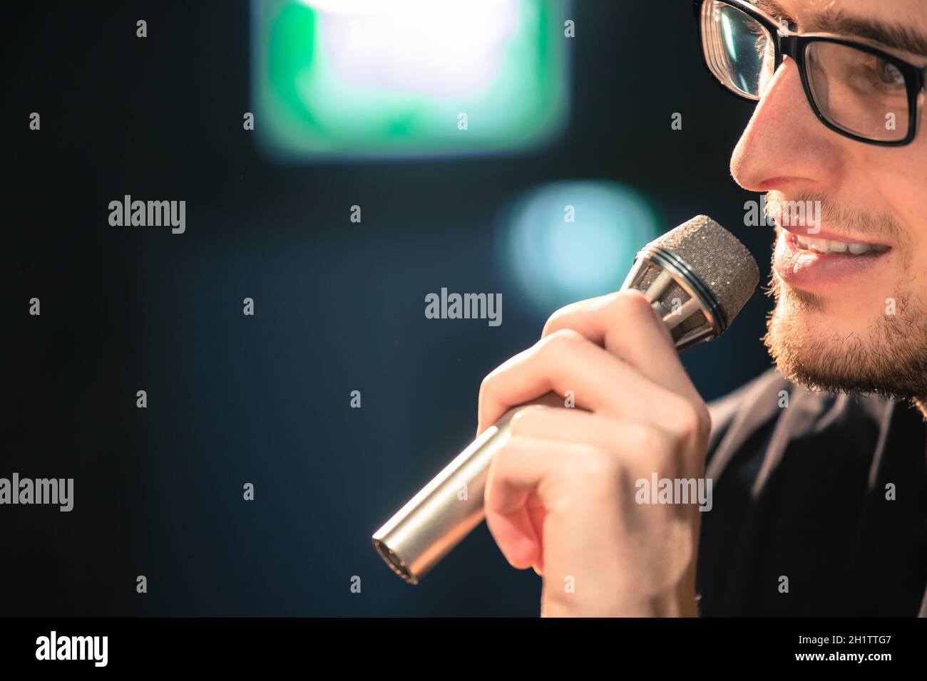 Young man on the stage is talking into a microphone, speech Stock Photo ...