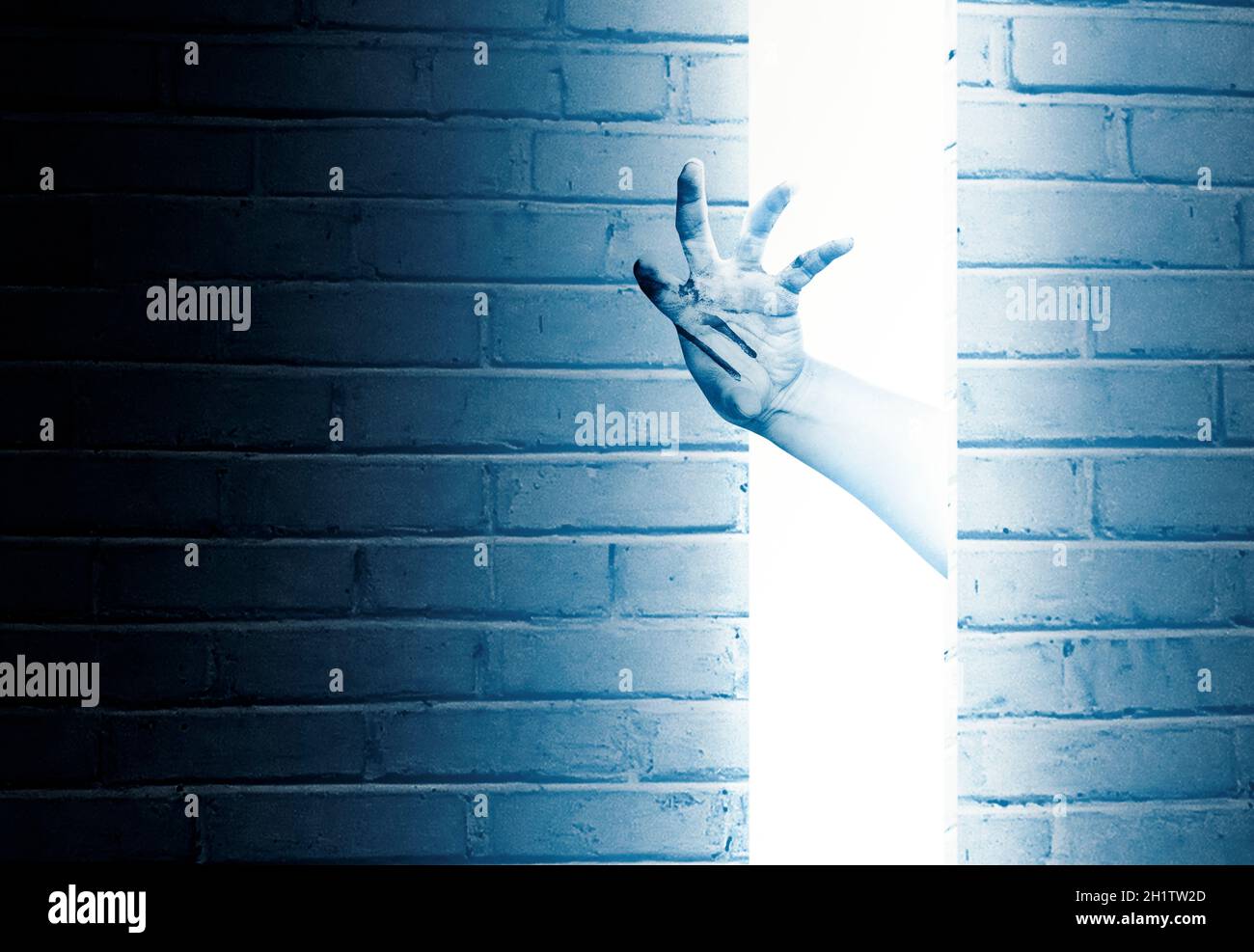 Zombie hand with blood and wound behind the brick wall with bright ...