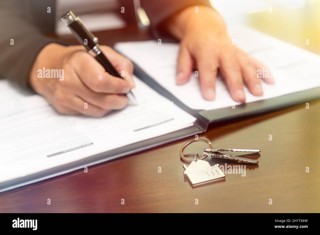 Woman signing real estate contract papers with house keys and home ...