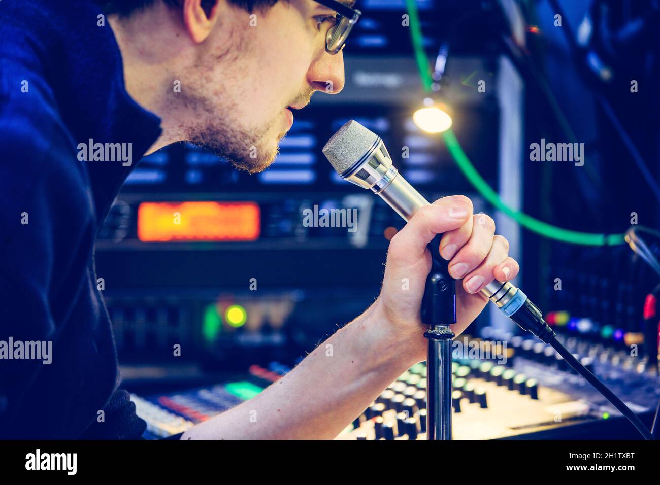 Young man is sitting in the recording studio and talks into the ...