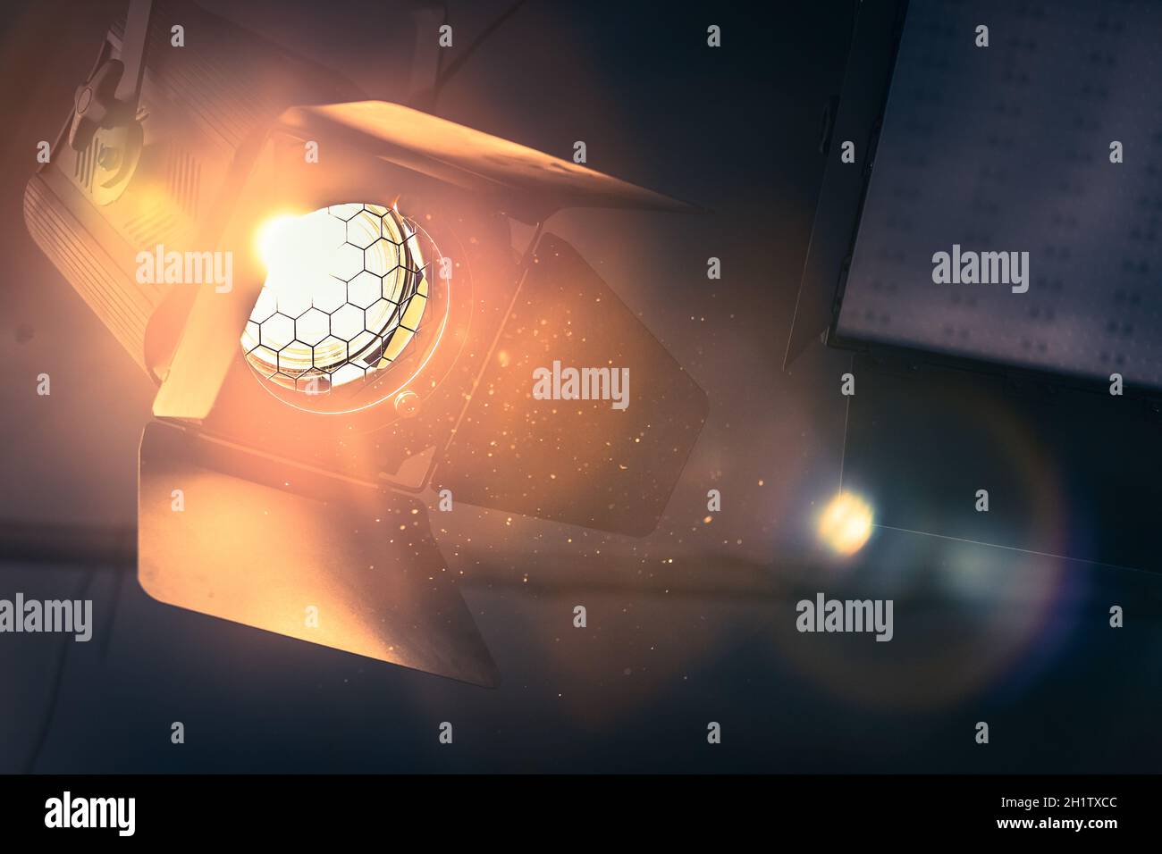 Professional orange studio spotlight hanging on the ceiling. Lighted ...