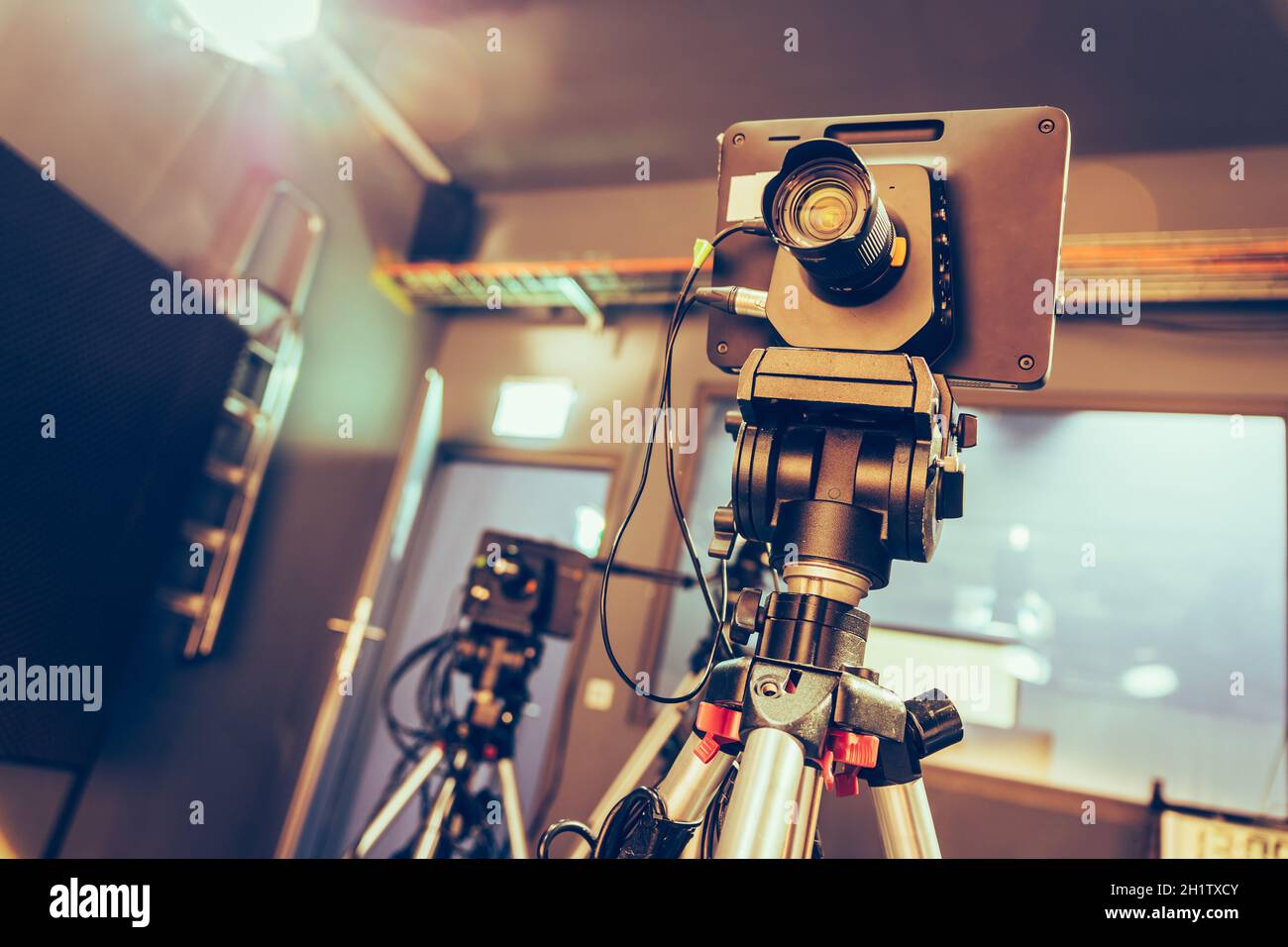 Film camera on a tripod in a television broadcasting studio, spotlights ...