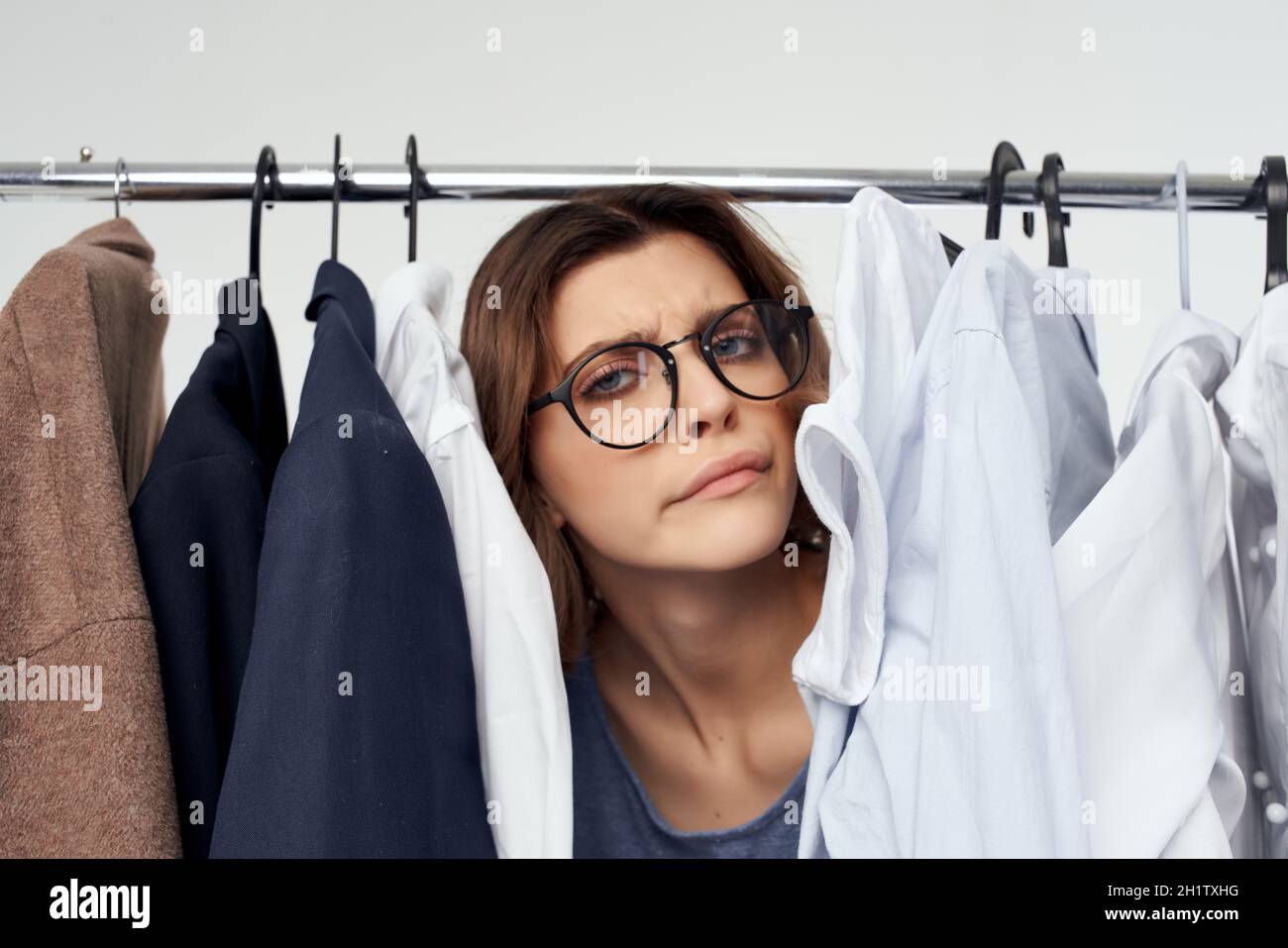 pretty woman near clothes shopaholic light background Stock Photo - Alamy