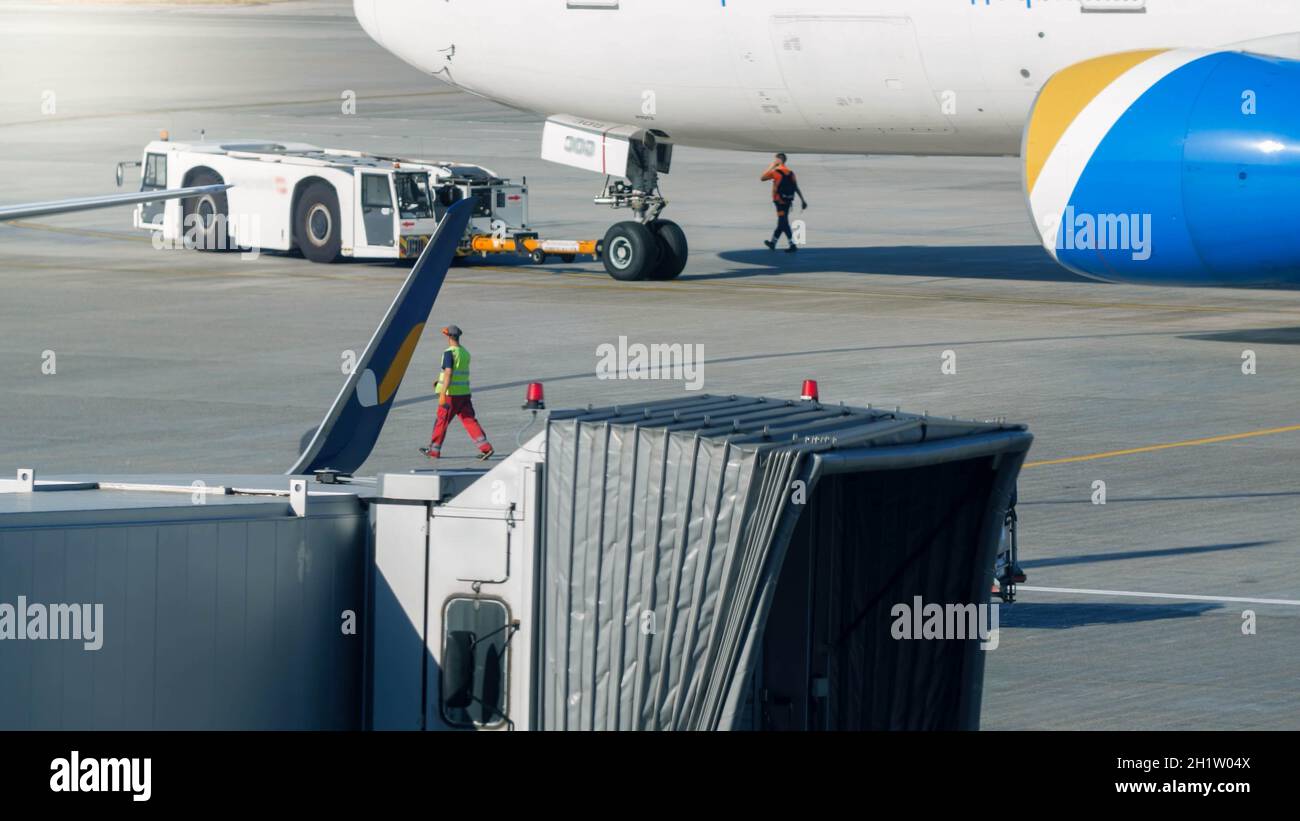 Special tractor pulling big airplane to the boarding gate in airplane ...