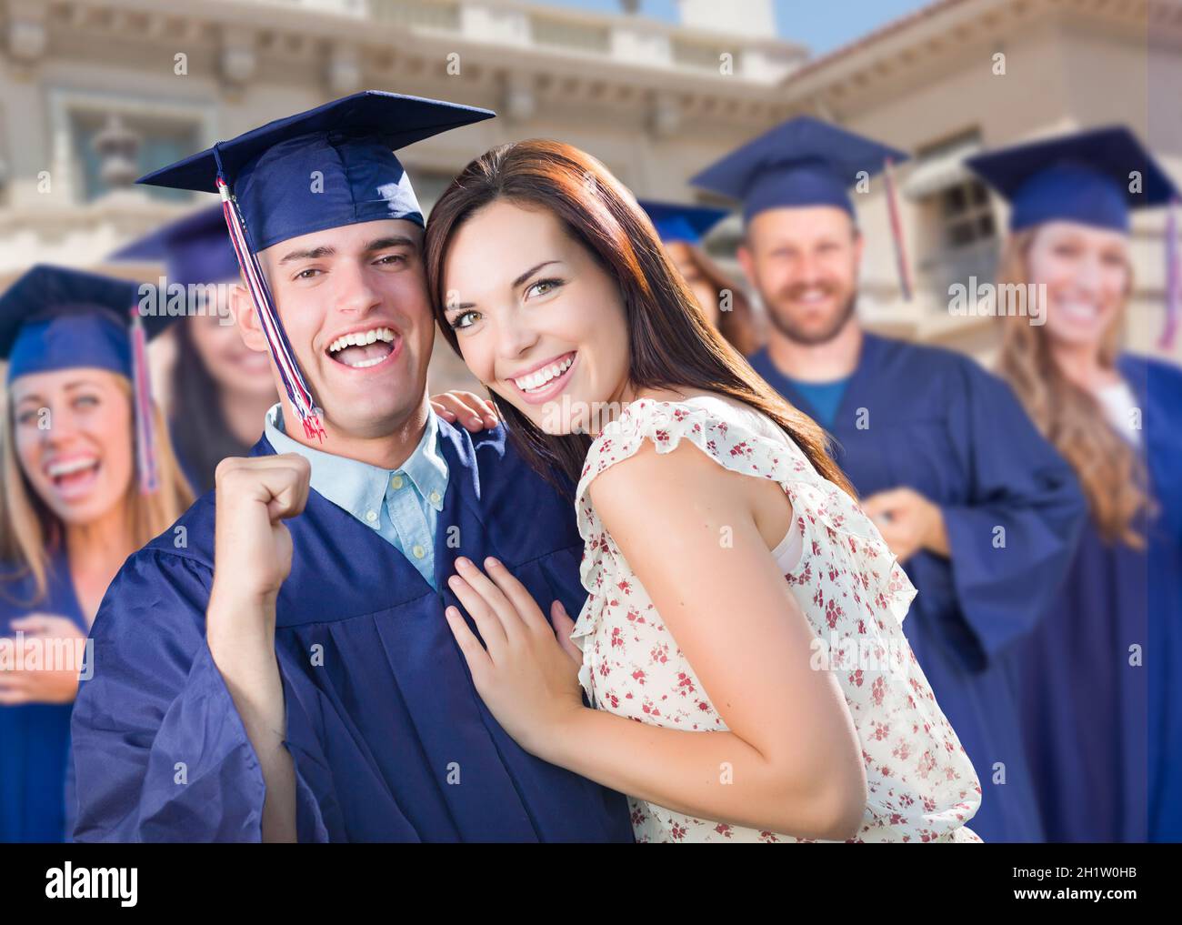 Proud Male Graduate In Cap and Gown with Girl Among Other Graduates ...