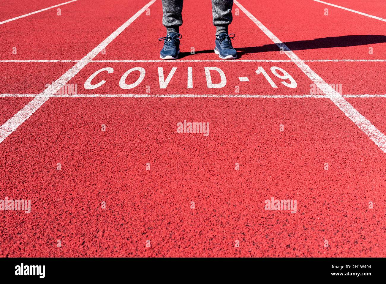 Win against virus. Athlete at the sprint start line in track with text ...