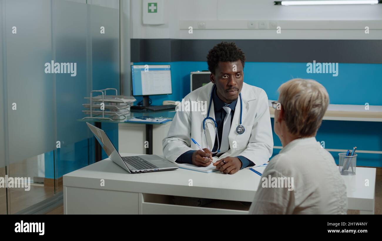 Doctor with healthcare expertise consulting elder woman sitting at desk ...