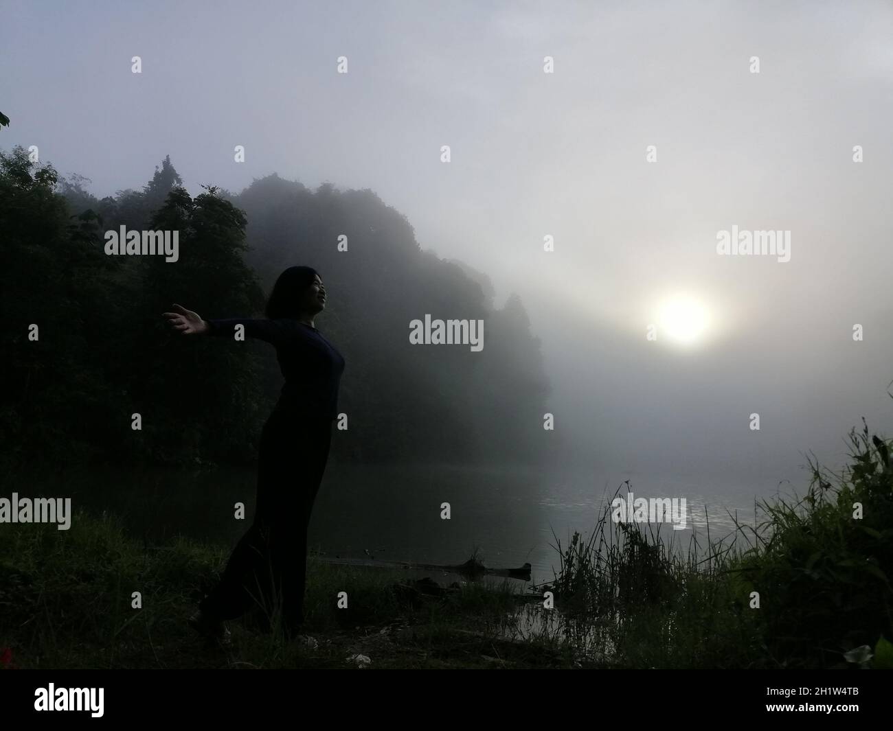 Young asian woman standing alone on lake enjoying peaceful moment of ...