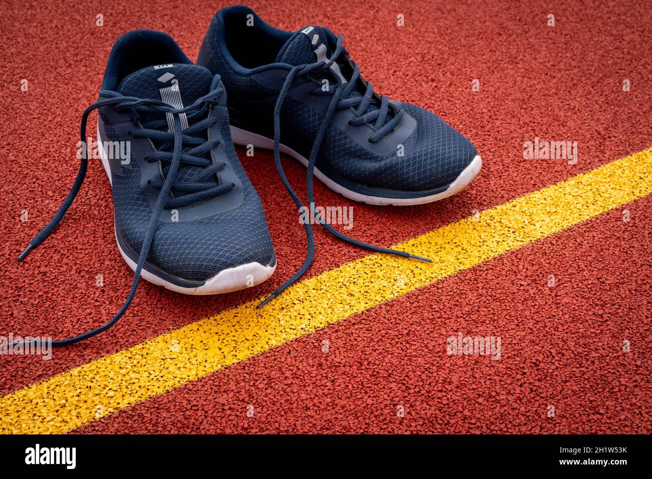 Running shoes are placed beside the start line on running track in the ...