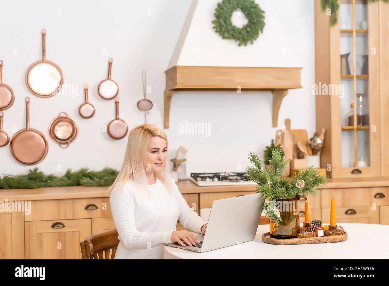 Smiling woman sitting surfing the internet on a laptop computer at home ...