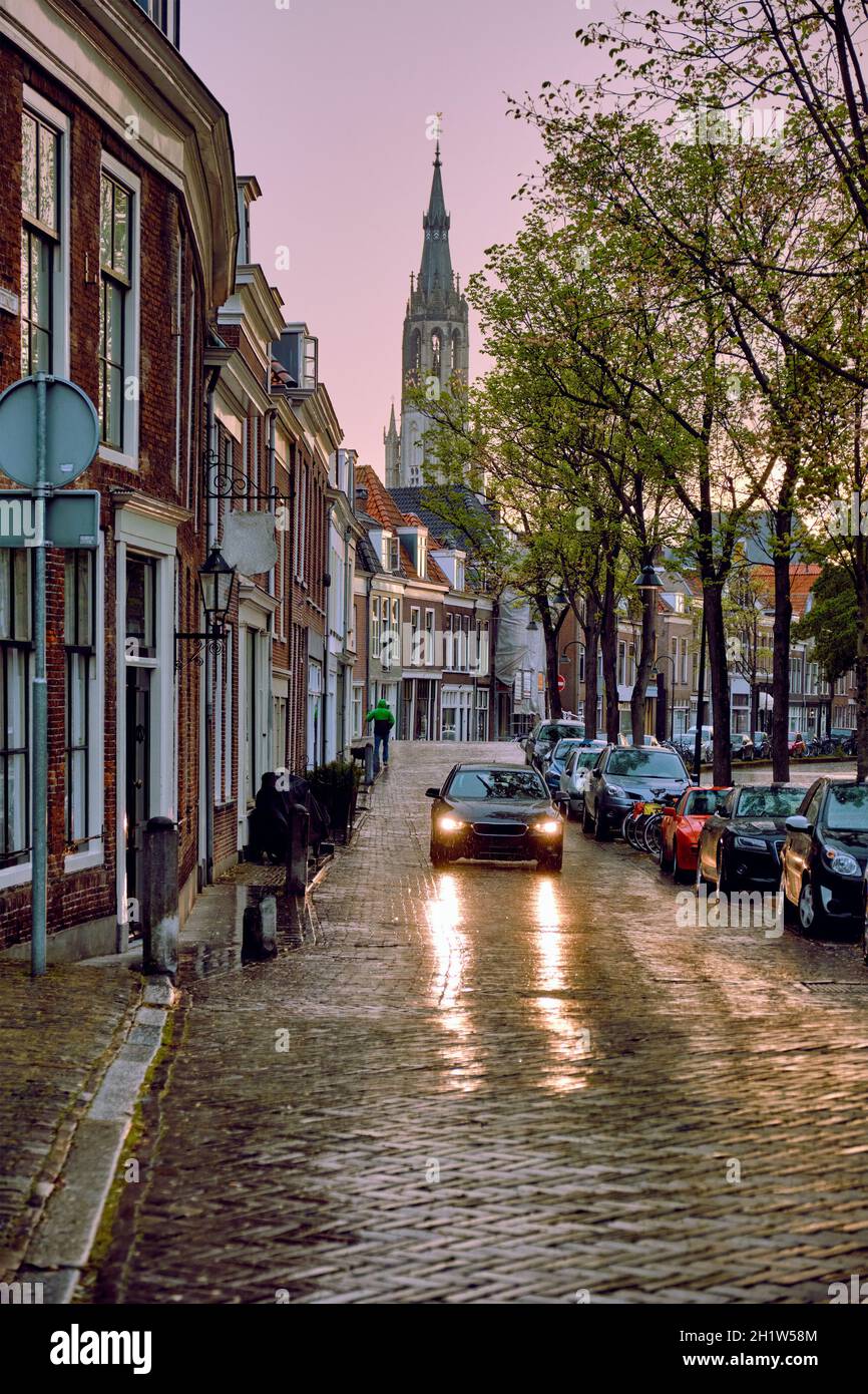Delft cobblestone street with car in the rain with Nieuwe Kerk church ...