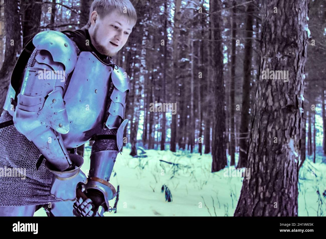 Knight in armor and with a sword in the middle of a winter forest ...