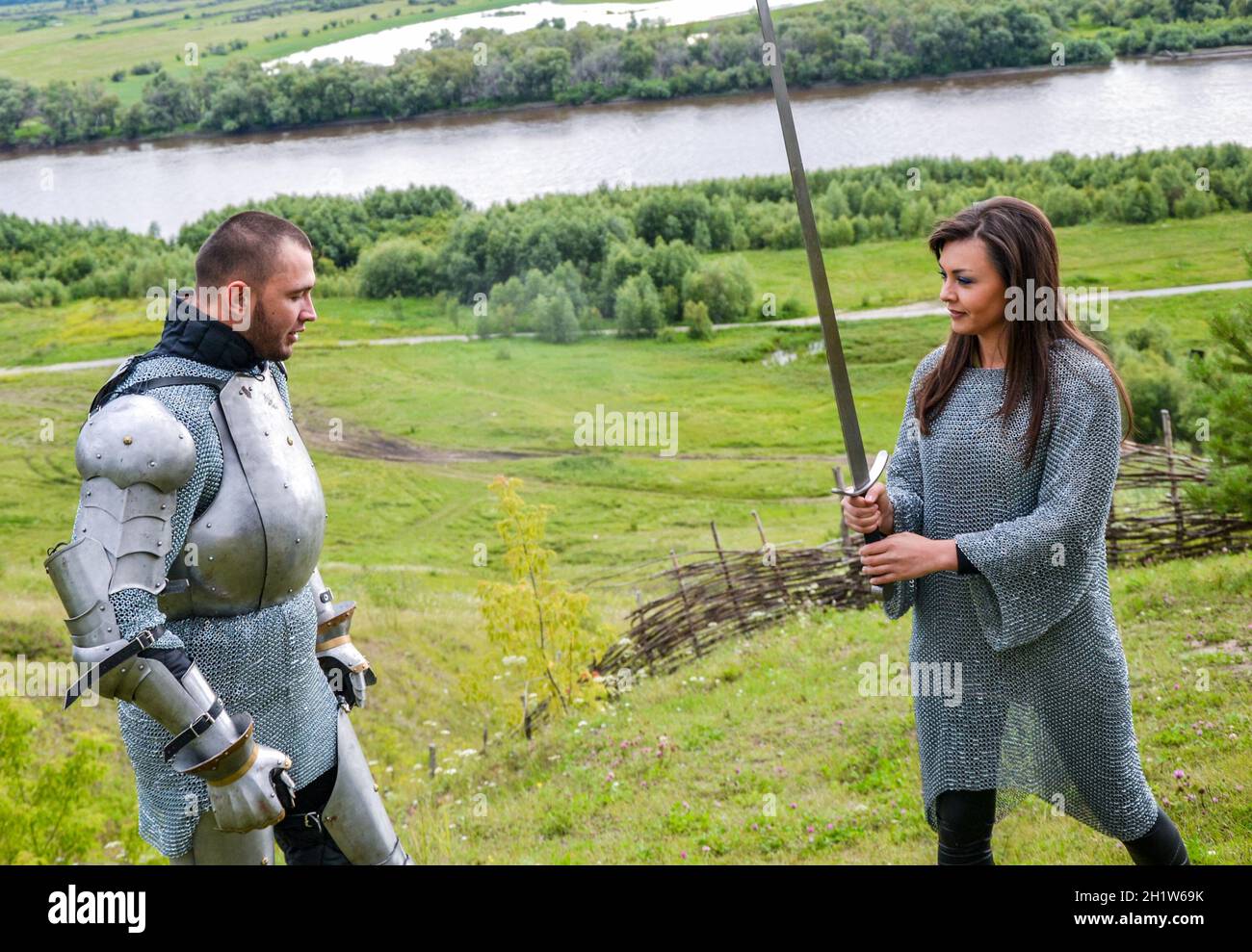 A lady in chain mail and a knight in armor learn to hold a weapon and ...