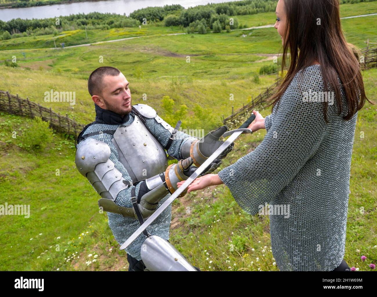 A lady in a chain mail hands a sword to her knight in armor. Knightly ...