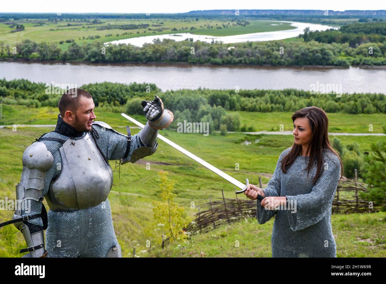 A lady in chain mail and a knight in armor learn to hold a weapon and ...