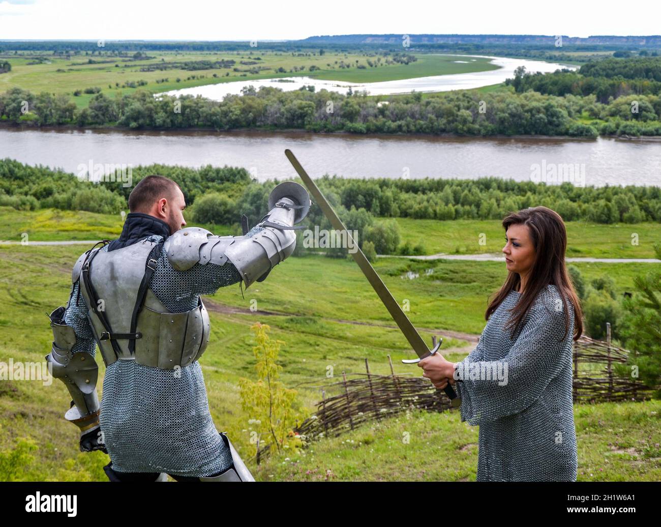 A lady in chain mail and a knight in armor learn to hold a weapon and ...