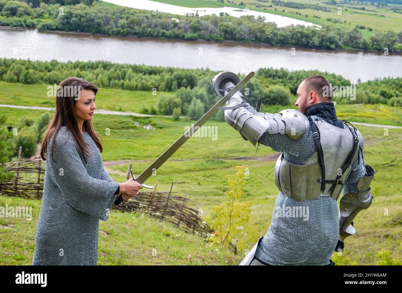 A lady in chain mail and a knight in armor learn to hold a weapon and ...