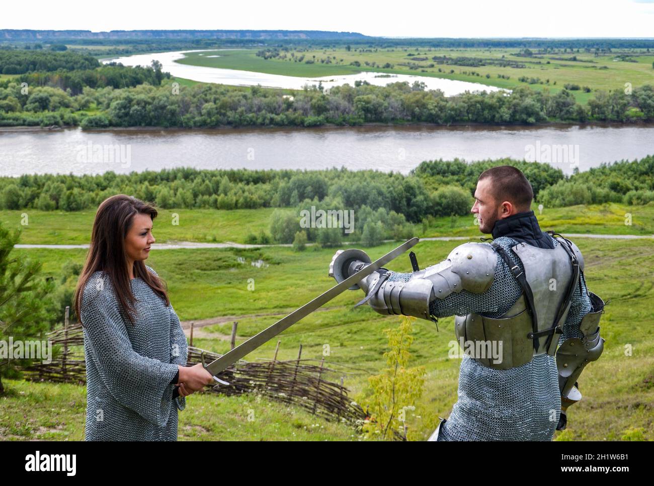 A lady in chain mail and a knight in armor learn to hold a weapon and ...
