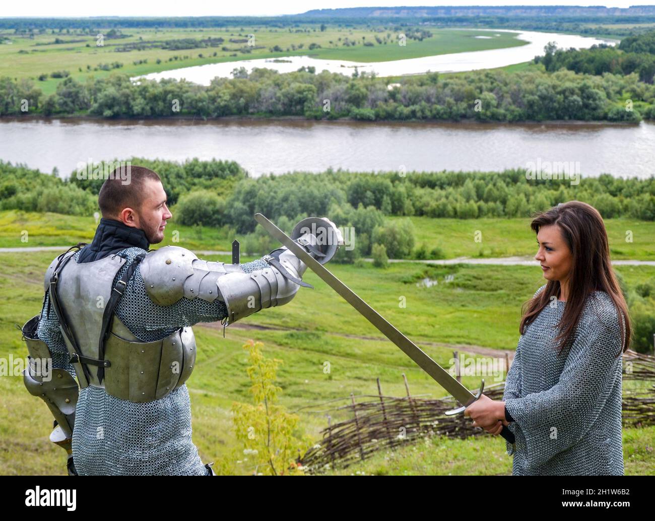 A lady in chain mail and a knight in armor learn to hold a weapon and ...