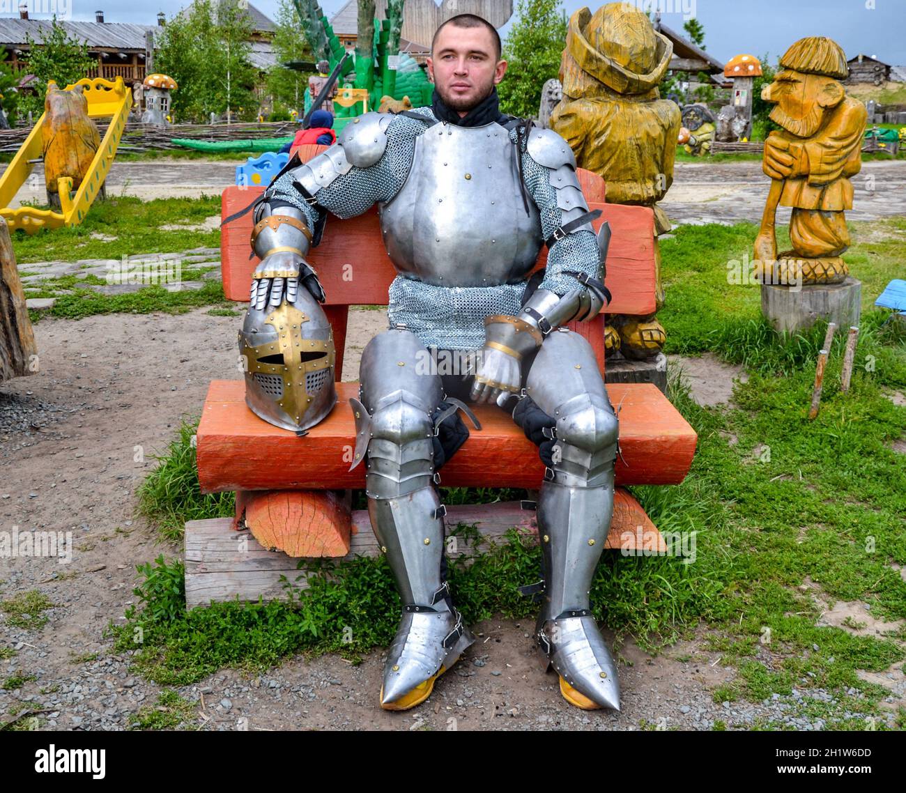 Knight in armor among wooden idols on a wooden bench. Knightly armor ...